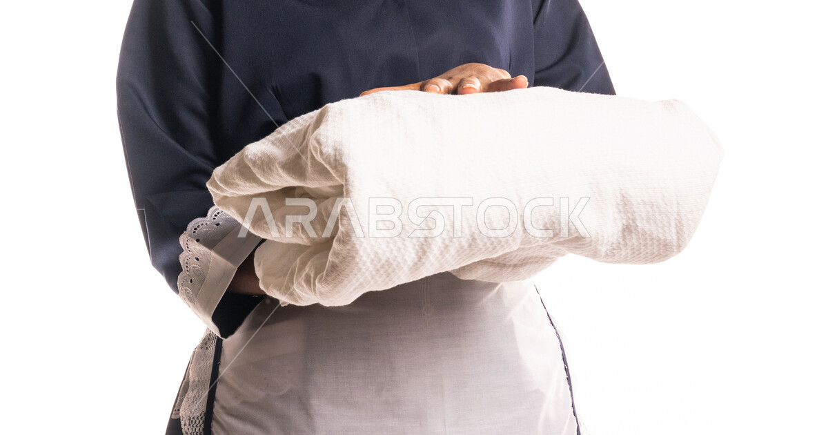بورتريه لعاملة نظافة ترتدي المئزر، تنظر إلى الكاميرا، تحمل بيدها منشفة