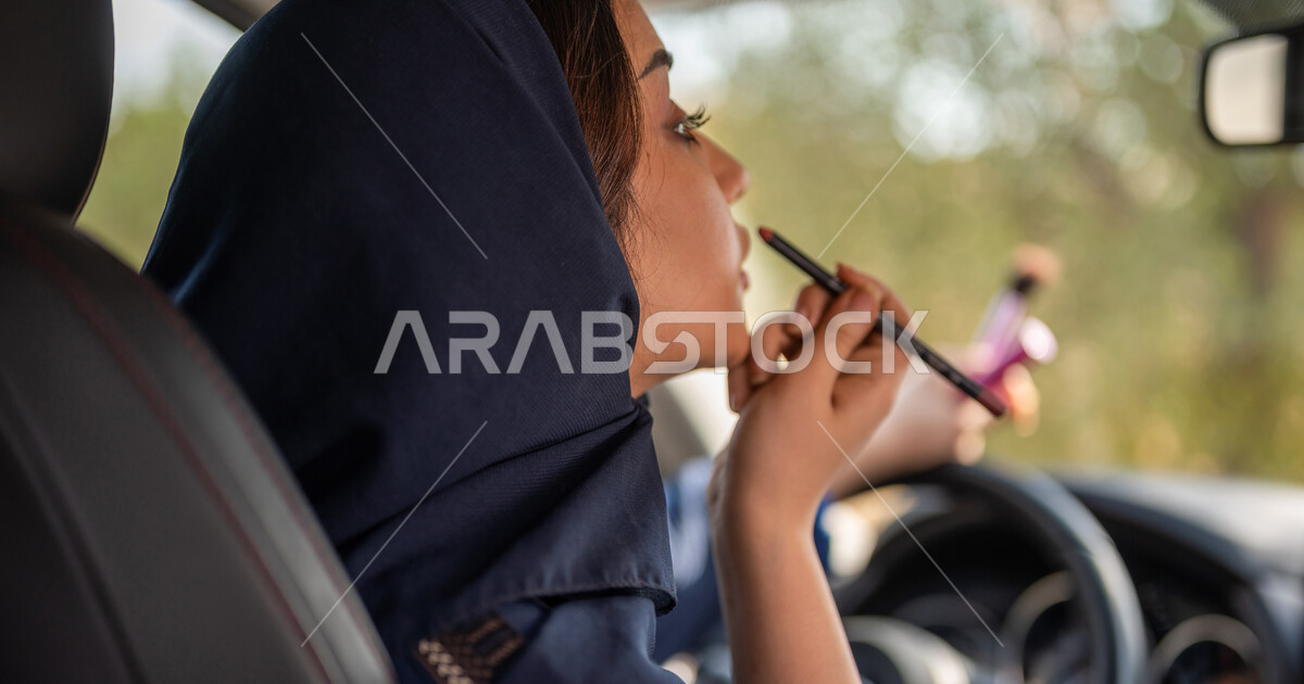 A veiled Saudi Arabian Gulf woman sitting in the car and decorating her ...