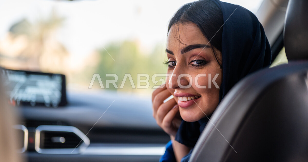 Close-up of a veiled Saudi Arabian Gulf woman riding in a car and ...