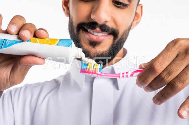 Close-up portrait of a Saudi Arabian Gulf man, brushing his teeth with ...