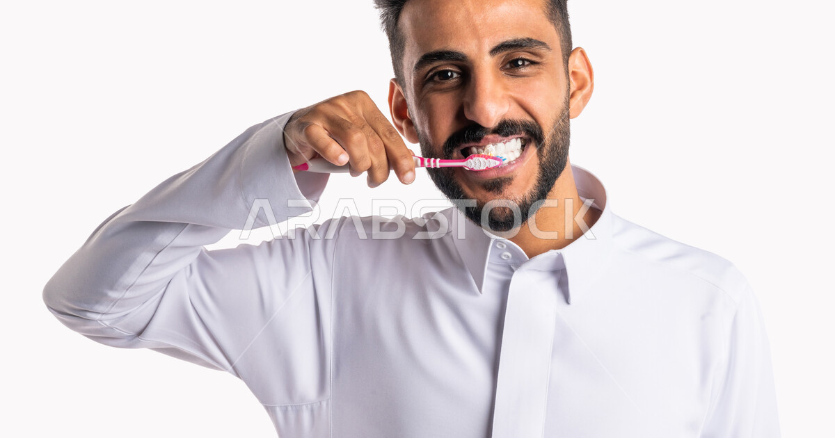 Close-up portrait of a Saudi Arabian Gulf man, brushing his teeth with ...
