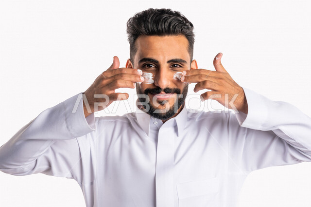 Close-up portrait of a Saudi Arabian Gulf man, applying moisturizing ...