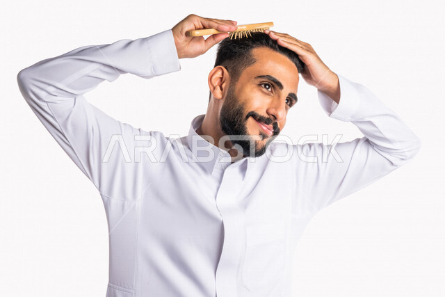 A close-up portrait of a Saudi Arabian Gulf man, styling his hair with ...