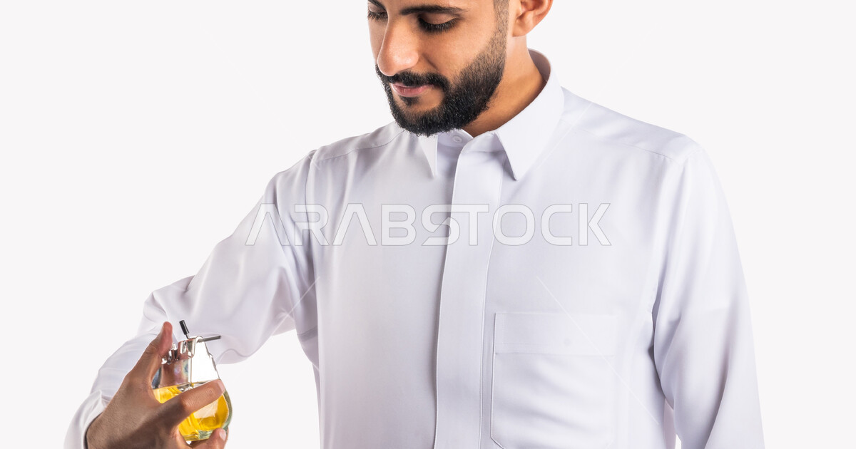 A close-up portrait of a Saudi Arabian Gulf man, applying perfume ...