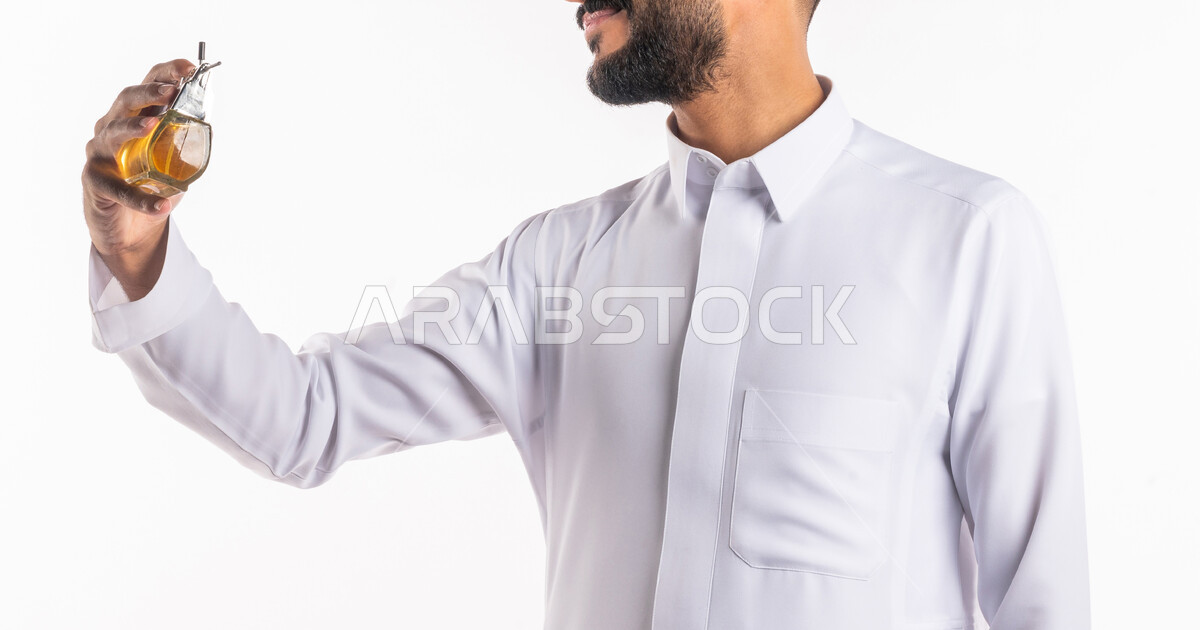 A close-up portrait of a Saudi Arabian Gulf man, applying perfume ...