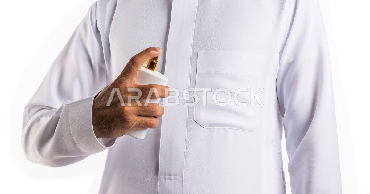 A close-up portrait of a Saudi Arabian Gulf man, applying perfume ...
