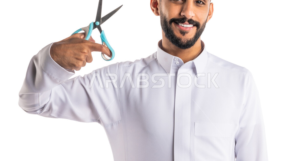 Portrait of a Saudi Arabian Gulf man, holding scissors in his hand ...