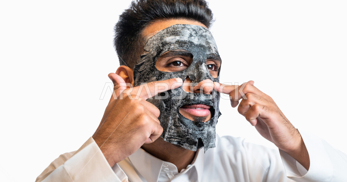 Portrait of a Saudi Arabian Gulf man, putting a clay mask on the face ...
