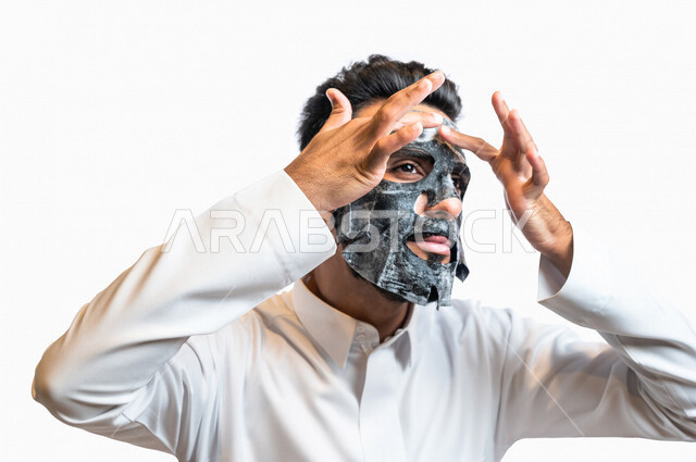 Portrait of a Saudi Arabian Gulf man, putting a clay mask on the face ...