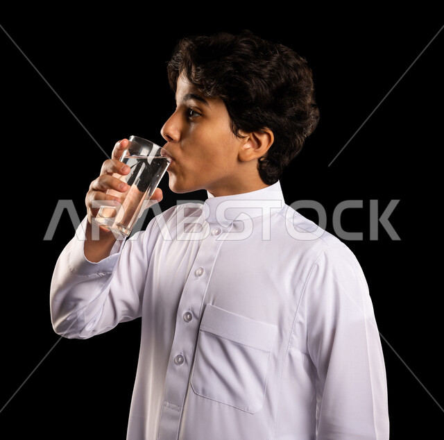 Portrait of a Saudi Arabian Gulf boy drinking water from a glass cup ...