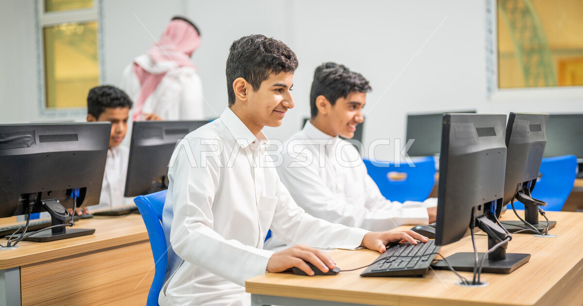 معلم عربي خليجي سعودي في معمل الحاسب الآلي، تعليم الطلبة كيفية استخدام