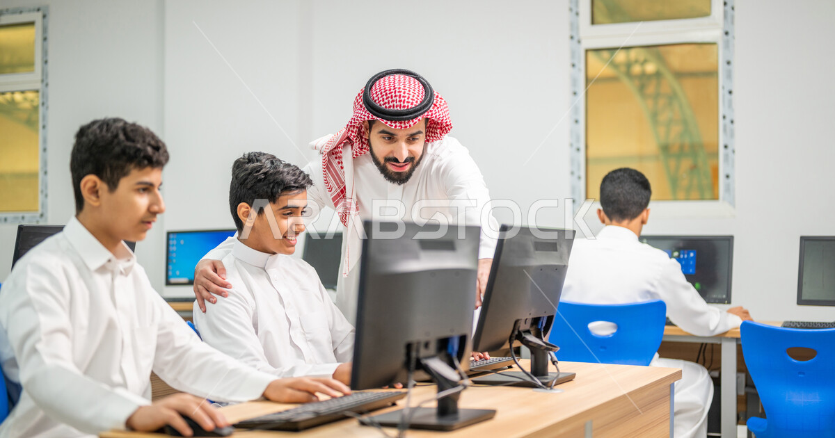 معلم عربي خليجي سعودي في معمل الحاسب الآلي، تعليم الطلبة كيفية استخدام