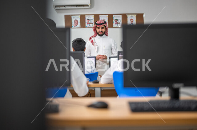 A close-up of computer screens, a Saudi Arabian Gulf teacher in the ...