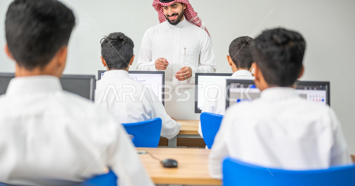 معلم عربي خليجي سعودي في معمل الحاسب الآلي، تعليم الطلبة كيفية استخدام