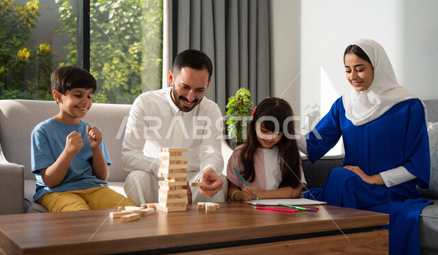 A Saudi Arabian Gulf family sitting in the living room, practicing ...
