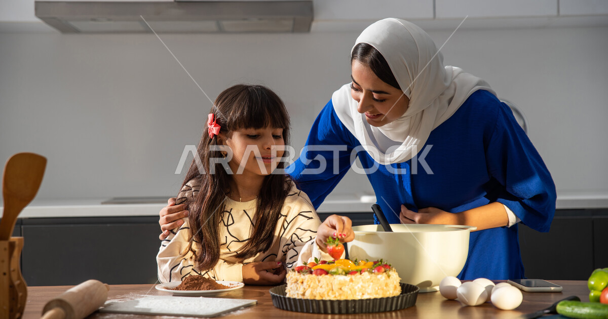 أم عربيه سعوديه خليجيه تشارك ابنتها في اعداد الحلوى في المطبخ، الوقوف ...