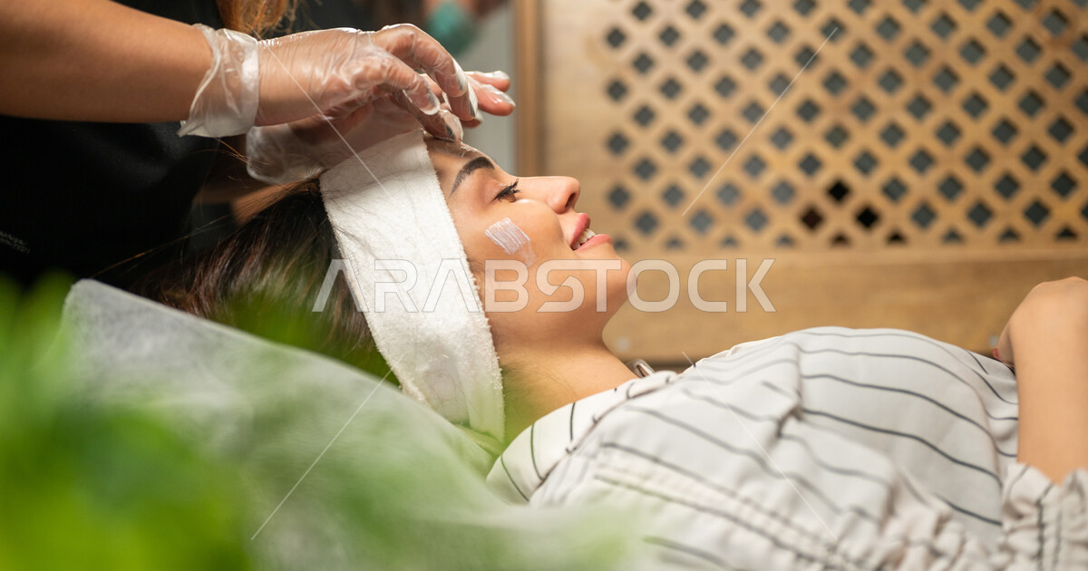 A Saudi Arabian Gulf woman in a women’s beauty salon, applying a ...