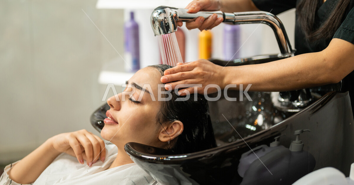A Saudi Arabian Gulf woman in a women’s beauty salon, a hairdresser who ...
