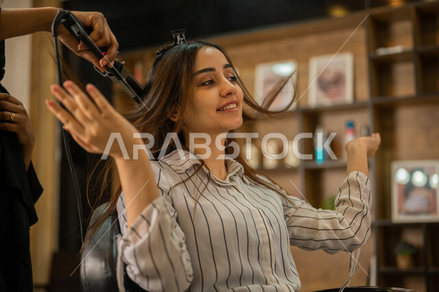 A Saudi Arabian Gulf woman in a women's beauty salon, a hairdresser ...