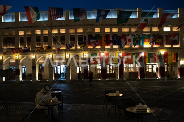 An Arab Gulf man wearing a ghutra and sitting in a cafe in Qatar, flags ...