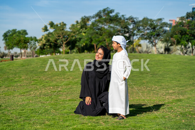 An Arab Emirati Gulf child playing with his mother in the park, facial ...