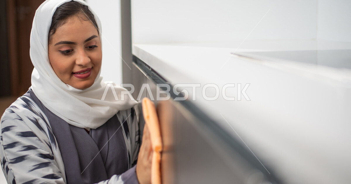 A Saudi Arab Gulf woman, removing dust using dust towels, routine ...