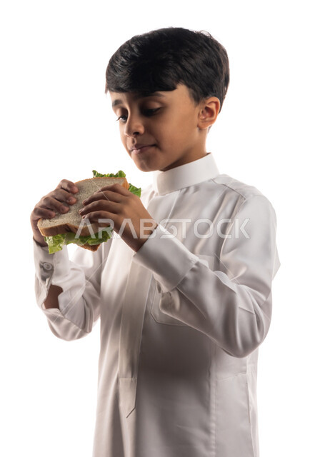 Portrait of a Saudi Arabian Gulf boy eating a sandwich, a healthy meal ...