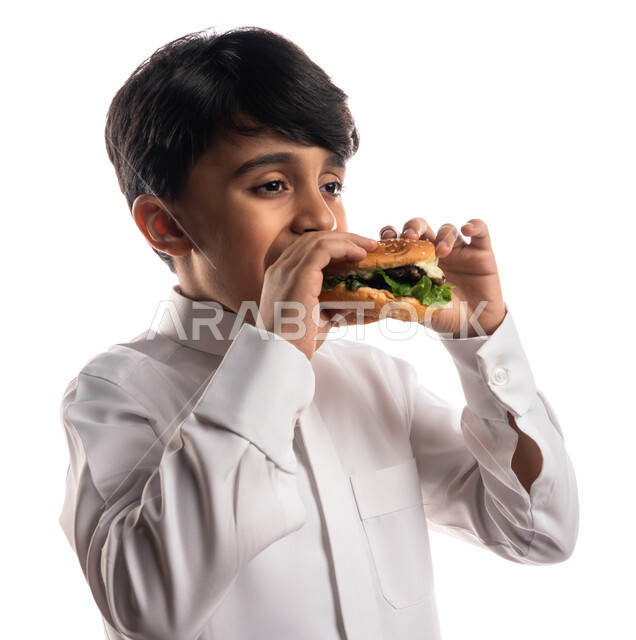 Portrait of a Saudi Arabian Gulf boy eating a burger sandwich, a ...