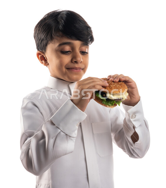 Portrait of a Saudi Arabian Gulf boy eating a burger sandwich, a ...