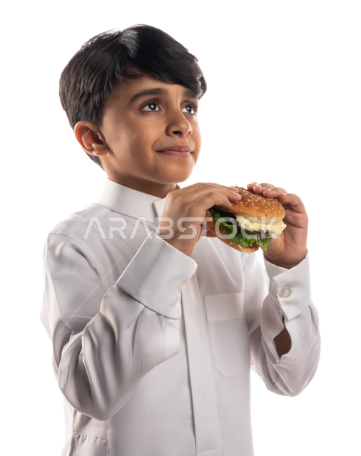 Portrait of a Saudi Arabian Gulf boy eating a burger sandwich, a ...