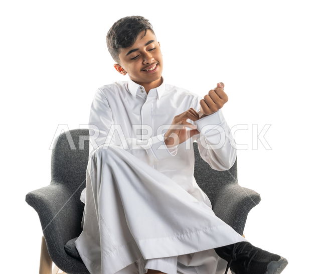 Portrait of a Saudi Arabian Gulf boy, sitting on a chair, wearing ...