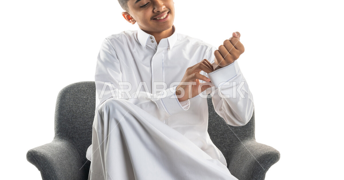 Portrait of a Saudi Arabian Gulf boy, sitting on a chair, wearing ...