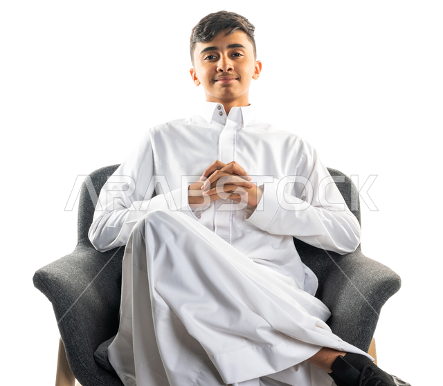 Portrait of a smiling Saudi Arabian Gulf boy, sitting on a chair ...