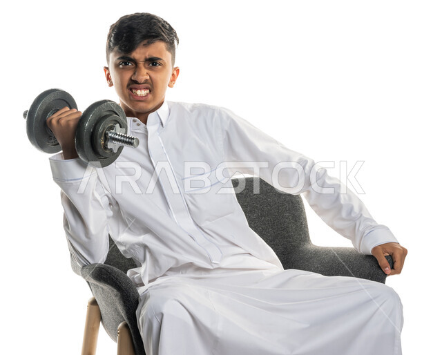 Portrait of a Saudi Arabian Gulf boy sitting on a chair, exercising ...