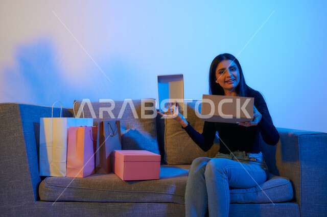Portrait of a Saudi Arabian Gulf woman holding colored gift boxes in ...