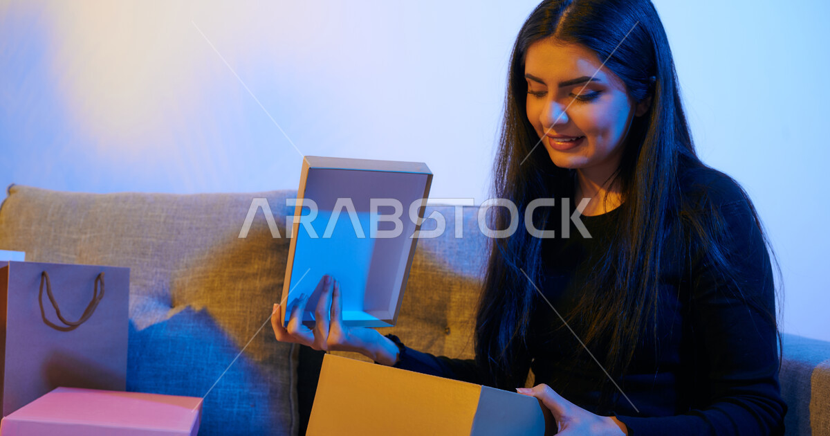 Portrait of a Saudi Arabian Gulf woman holding colored gift boxes in ...