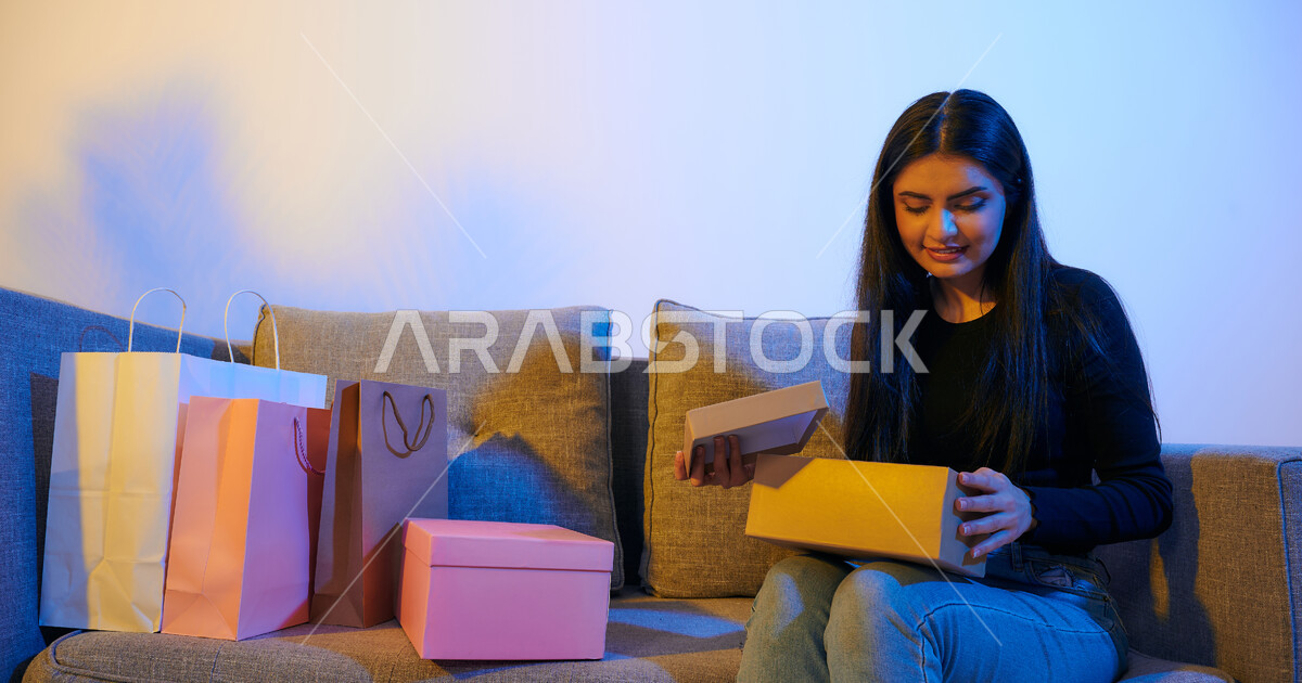 Portrait of a Saudi Arabian Gulf woman holding colored gift boxes in ...
