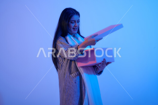 Portrait of a Saudi Arabian Gulf woman holding colored gift boxes in ...