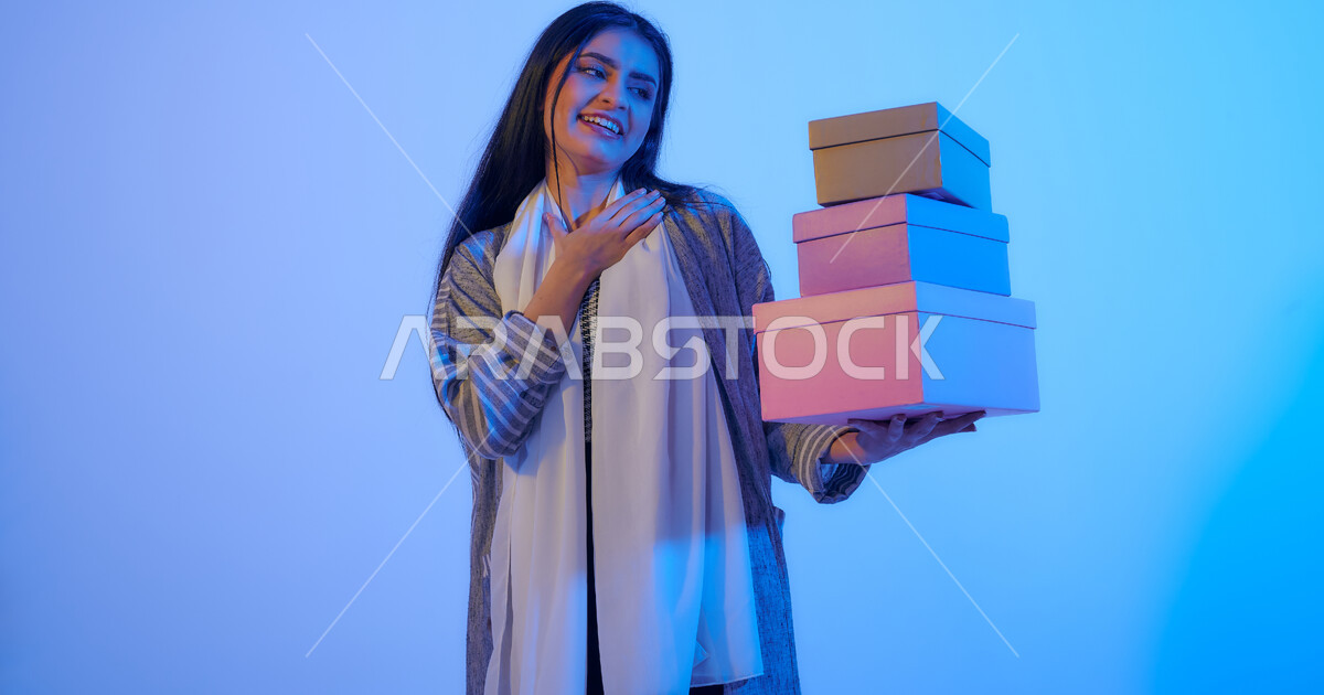 Portrait of a Saudi Arabian Gulf woman holding colored gift boxes in ...