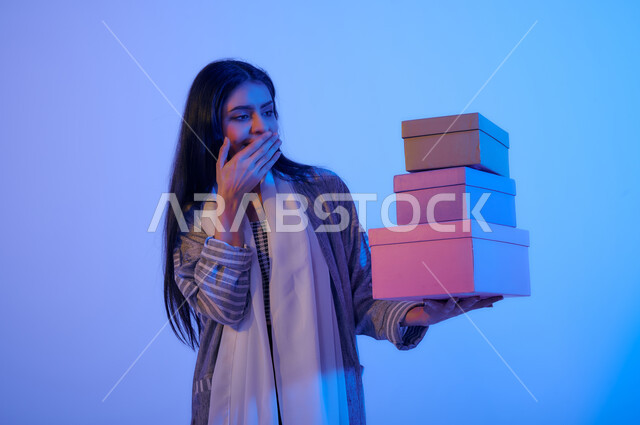 Portrait of a Saudi Arabian Gulf woman holding colored gift boxes in ...