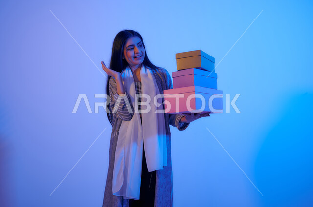Portrait of a Saudi Arabian Gulf woman holding colored gift boxes in ...