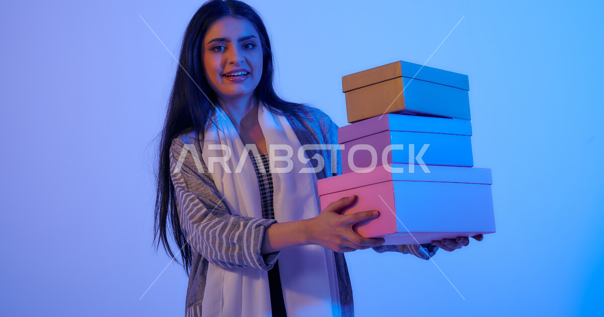 Portrait of a Saudi Arabian Gulf woman holding colored gift boxes in ...