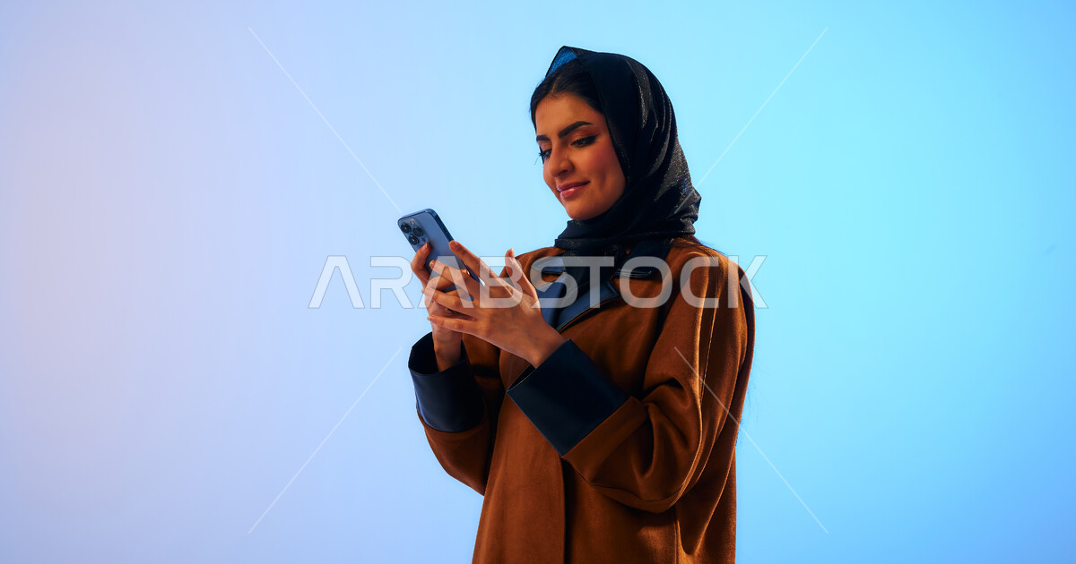 Portrait of a Saudi Arab Gulf woman, holding a mobile phone in her hand ...