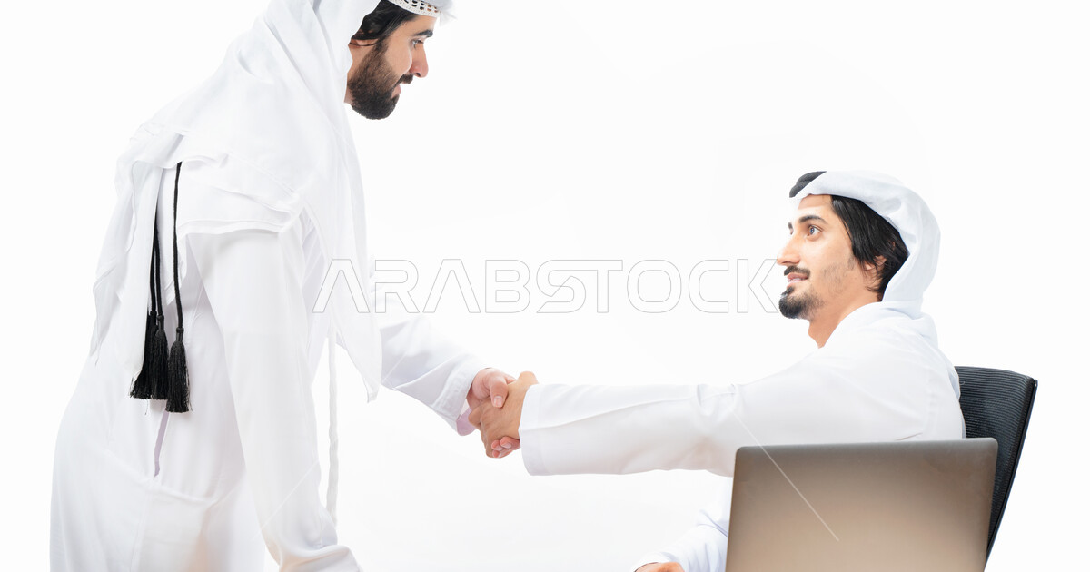Portrait of two Arab Gulf Emirati businessmen shaking hands, completing ...