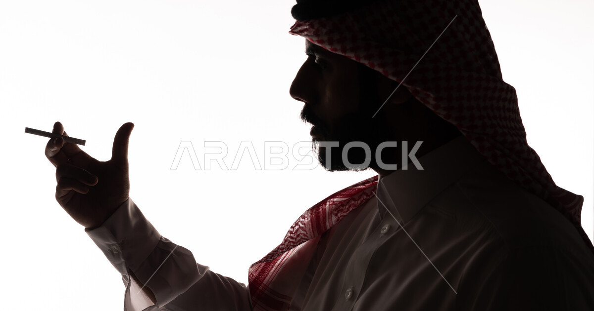 Portrait, silhouette of a Saudi Arabian Gulf man, smoking a cigarette ...