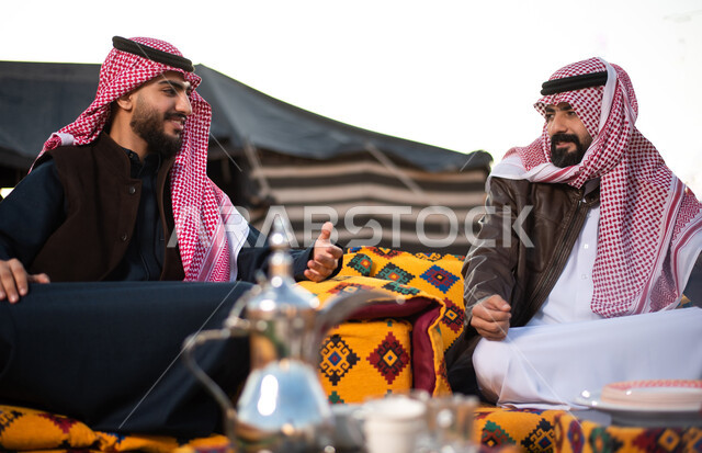 Two Saudi Arab Gulf men dressed in warm winter clothes and enjoying a ...