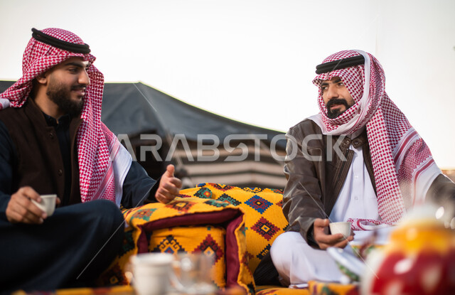 Two young Saudi Arabian Gulf men dressed in warm winter clothes, a wild ...