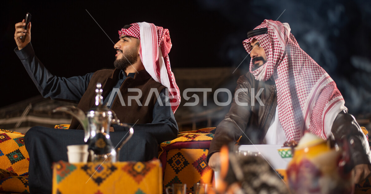 Two Saudi Arab men dressed in traditional Saudi dress, taking selfies ...