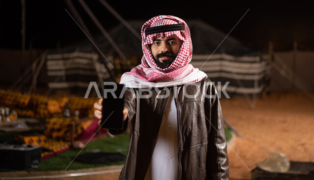 A Saudi Arabian Gulf man wearing warm winter clothes and using a mobile ...