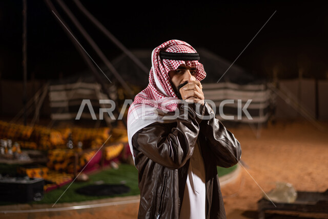 A Saudi Arabian Gulf man wearing a winter jacket and blowing with his ...
